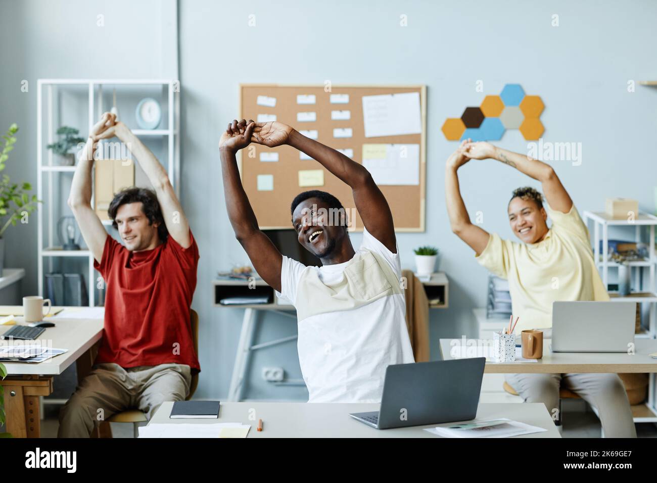 Diverse group of smiling young people doing stretching exercises at ...
