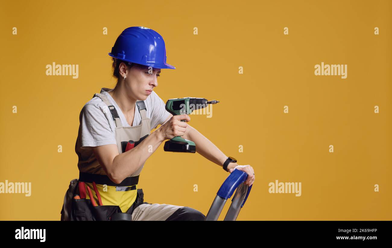 Confident constructor using electric power drill to screw nails ...