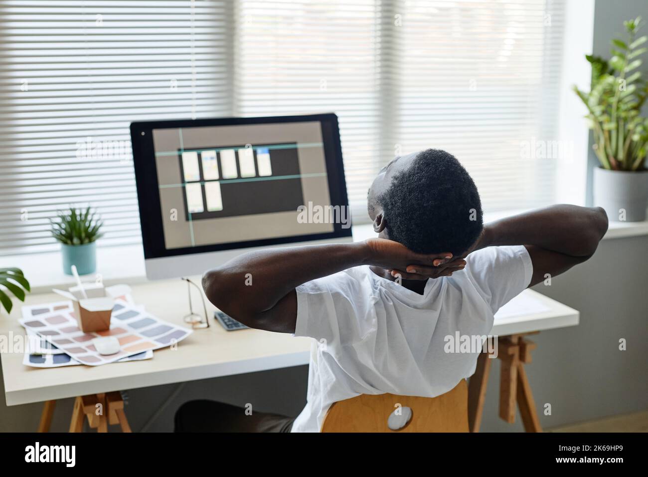 Back view of tired black man stretching muscles at office workplace ...