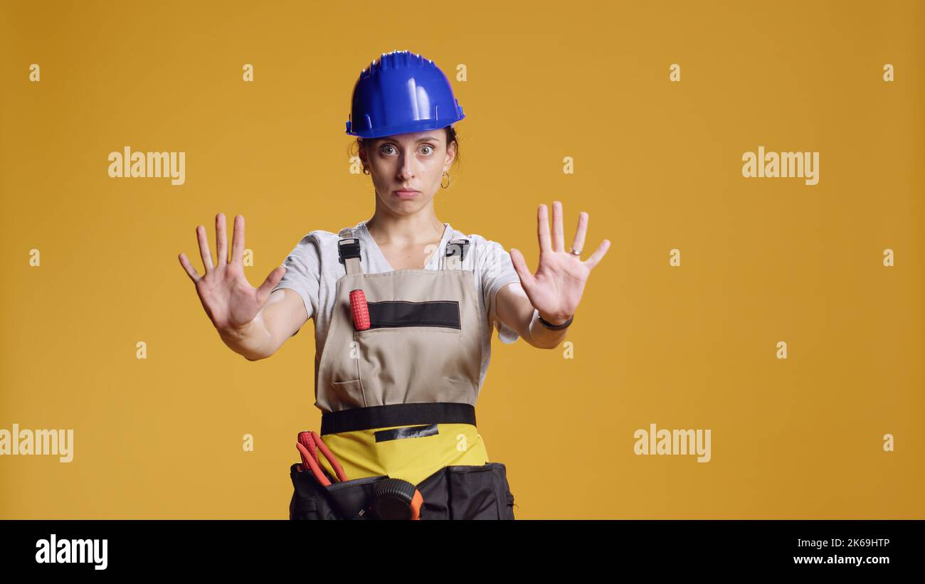 Portrait of construction worker doing stop sign with palm, advertising ...