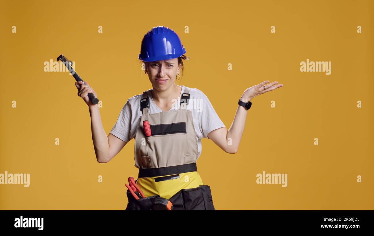 Portrait of confused handywoman raising shoulders and doing i dont know ...