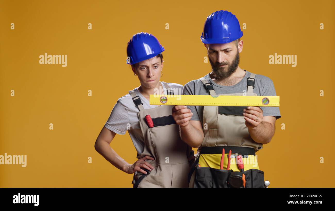Construction workers using water level tools to measure flat surface ...