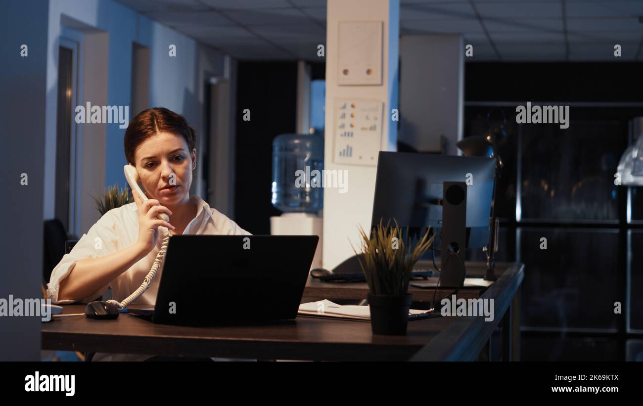 Empowered female manager talking on landline phone call, working late ...