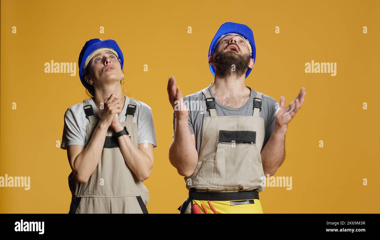 Portrait of construction workers praying for help, wearing hardhats and ...