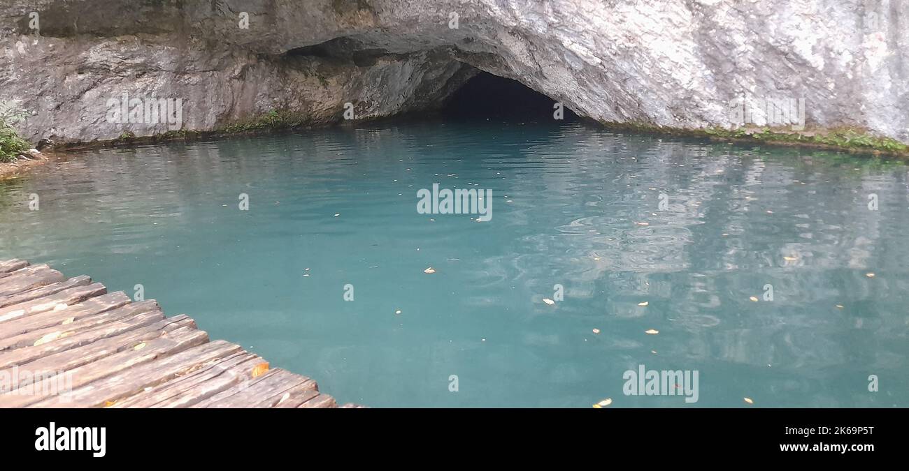 The beautiful flowing blue water under a stone leading into a cave ...