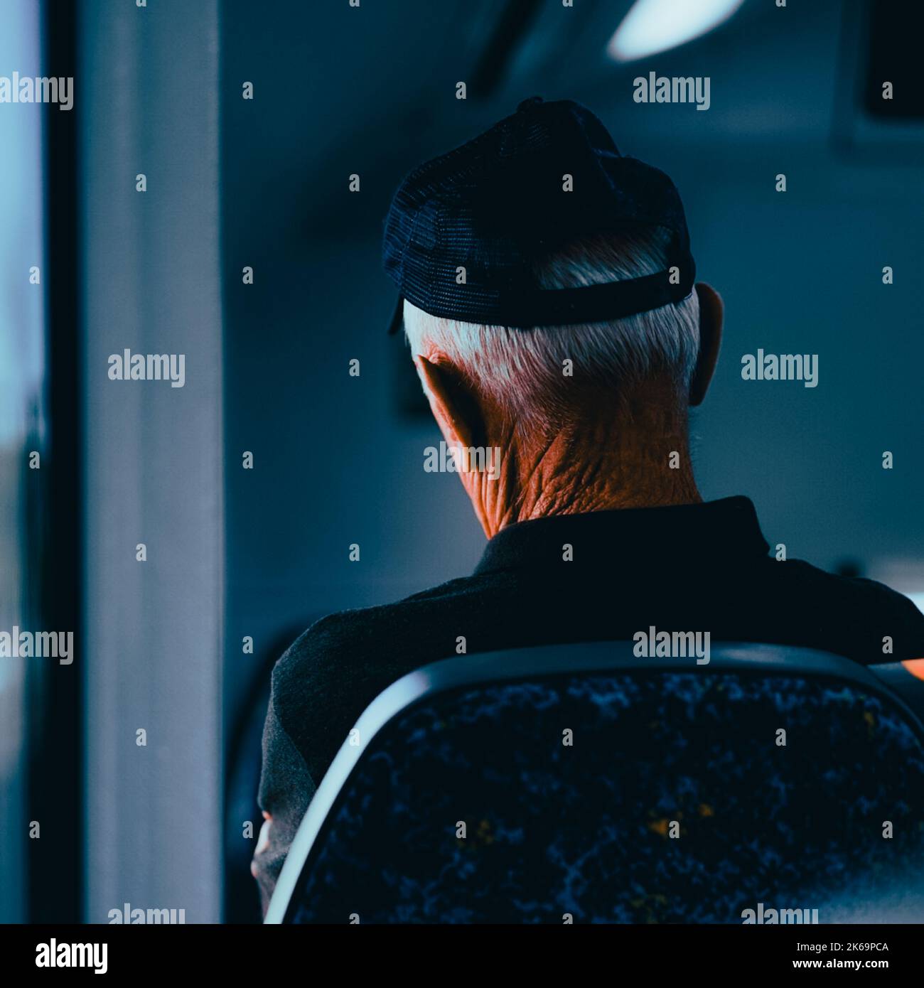 A vertical back view of a sitting old man with a wrinkled neck and a ...