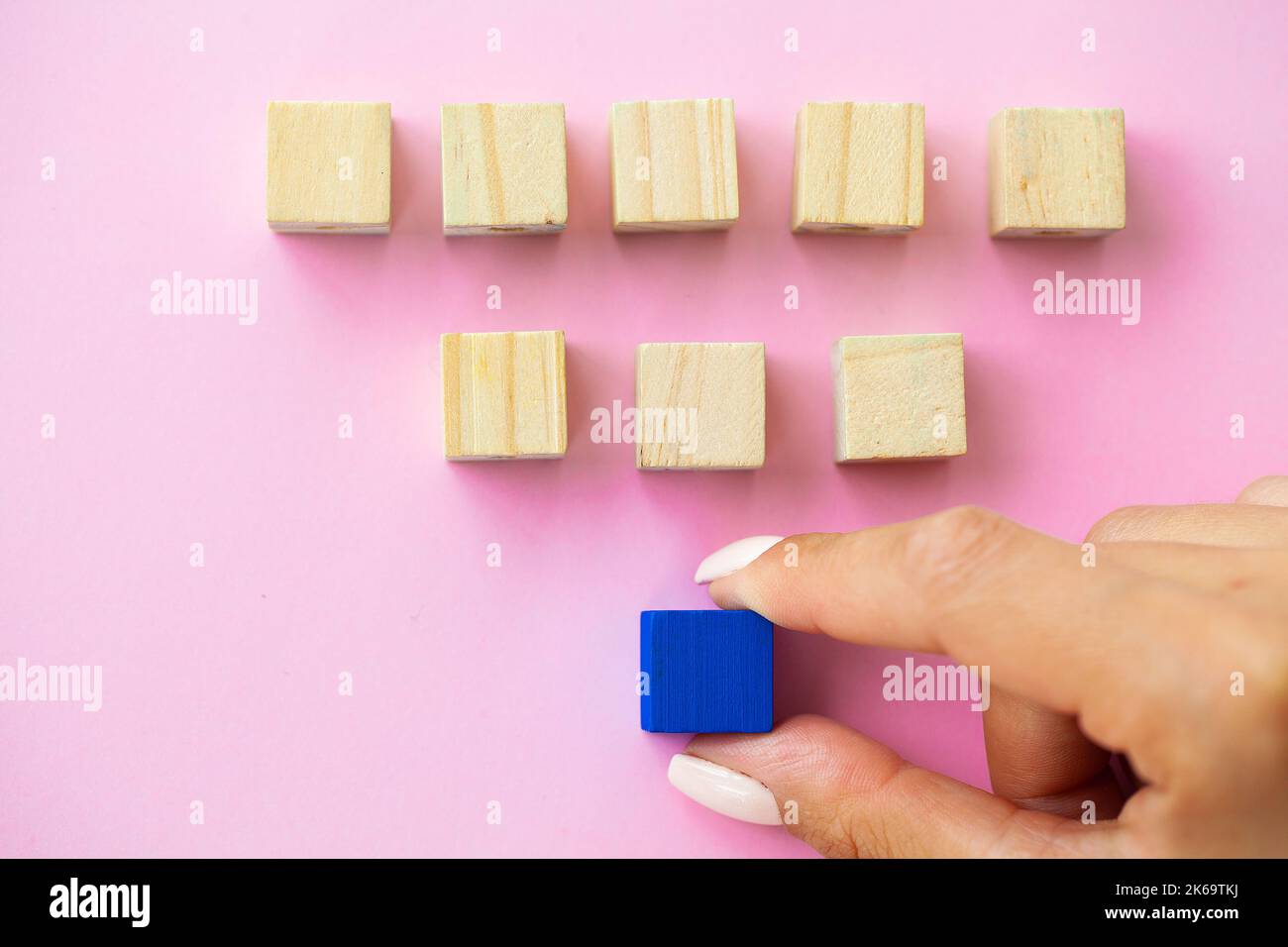 Wooden blocks with a human hand placing one cube at the top on pink ...