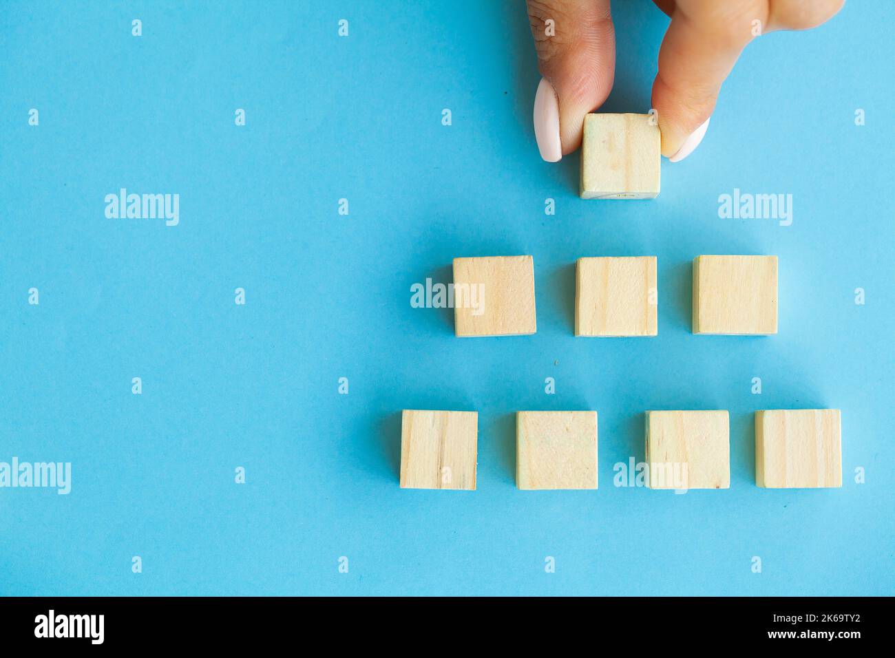 Woman hand arranging empty wood block and copy space on blue and pink ...