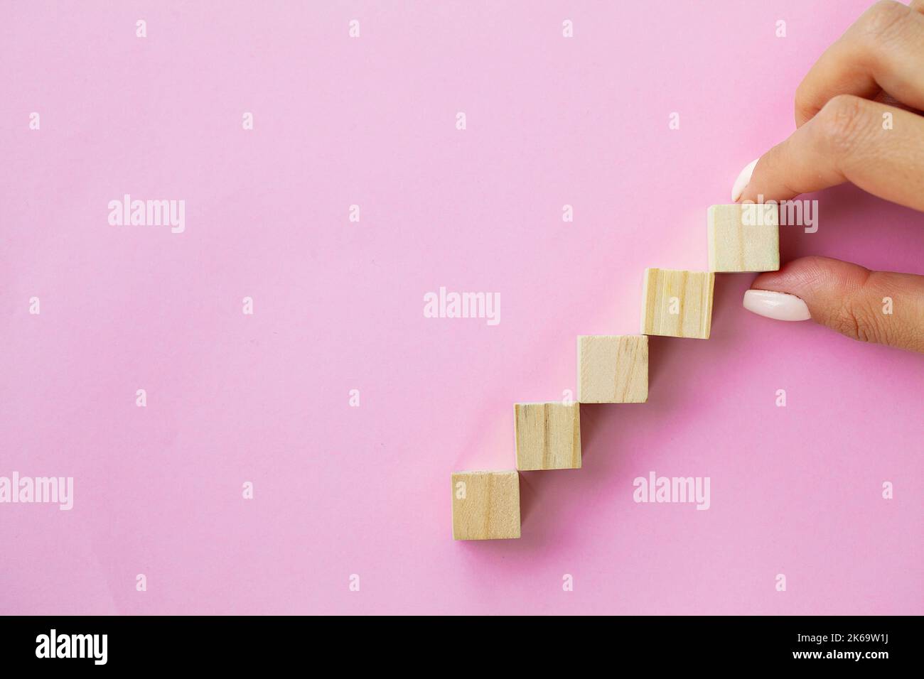 Woman hand arranging empty wood block and copy space on blue and pink ...