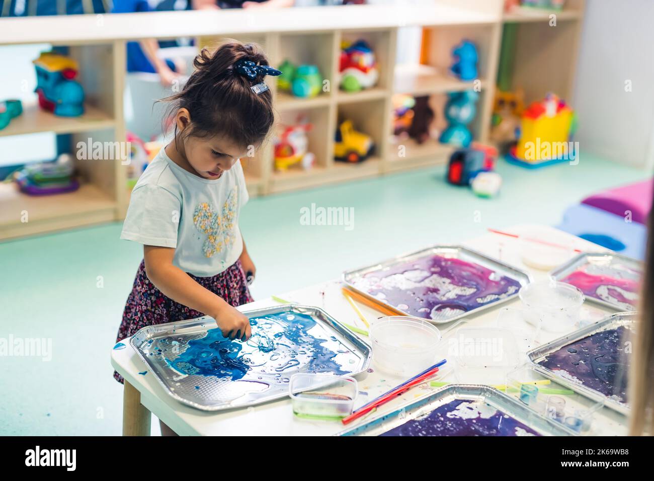 preschooler standing at the table and putting her hands in the ...