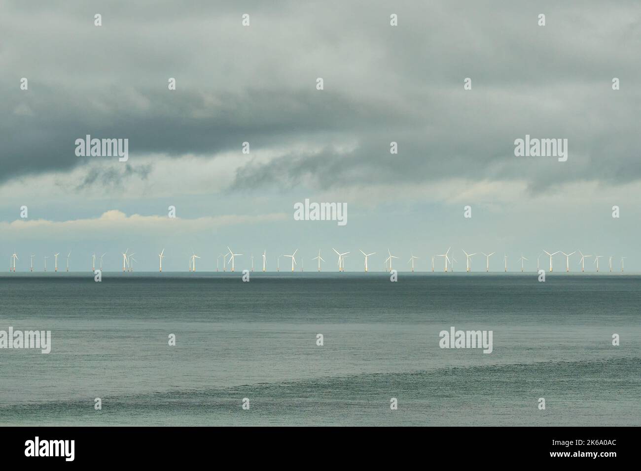 Offshore wind turbines in the sun on the horizon under grey clouds ...