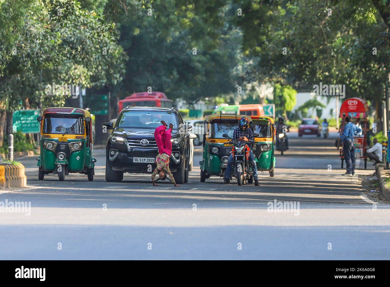 A poor girl child performs acrobatics in front of vehicles at a traffic ...