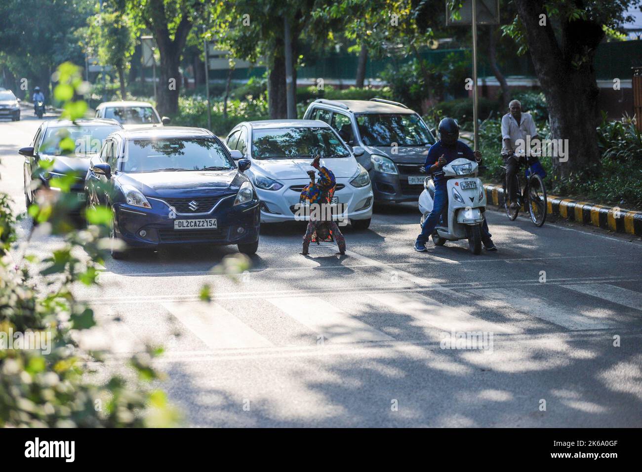 A poor girl child performs acrobatics in front of vehicles at a traffic ...