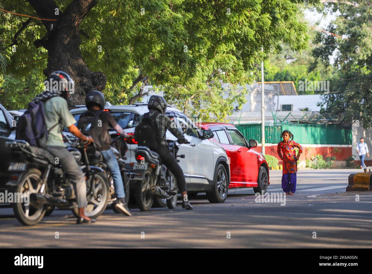 A poor girl child performs acrobatics in front of vehicles at a traffic ...