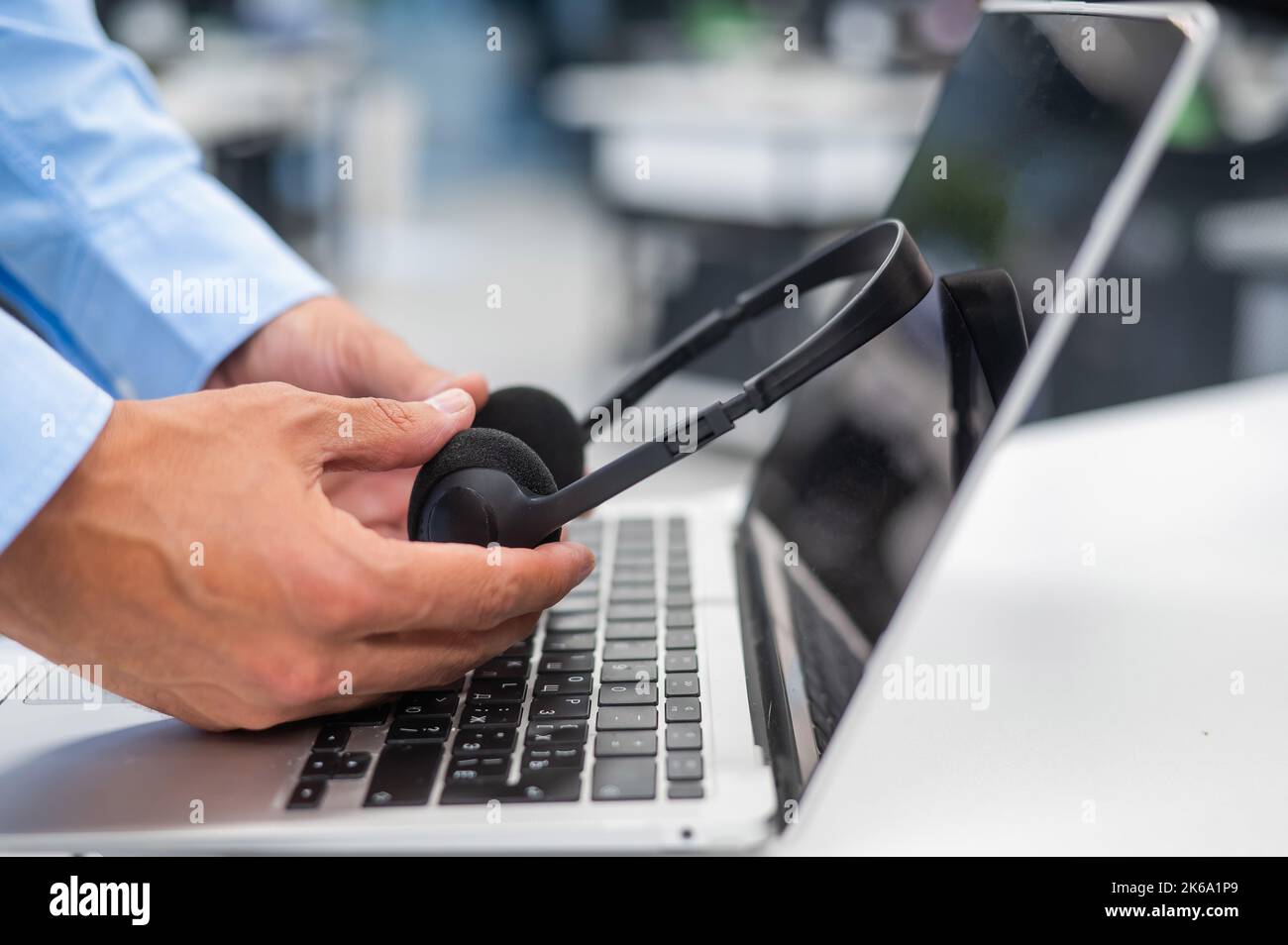 A man puts a headset on a laptop keyboard in the office Stock Photo - Alamy