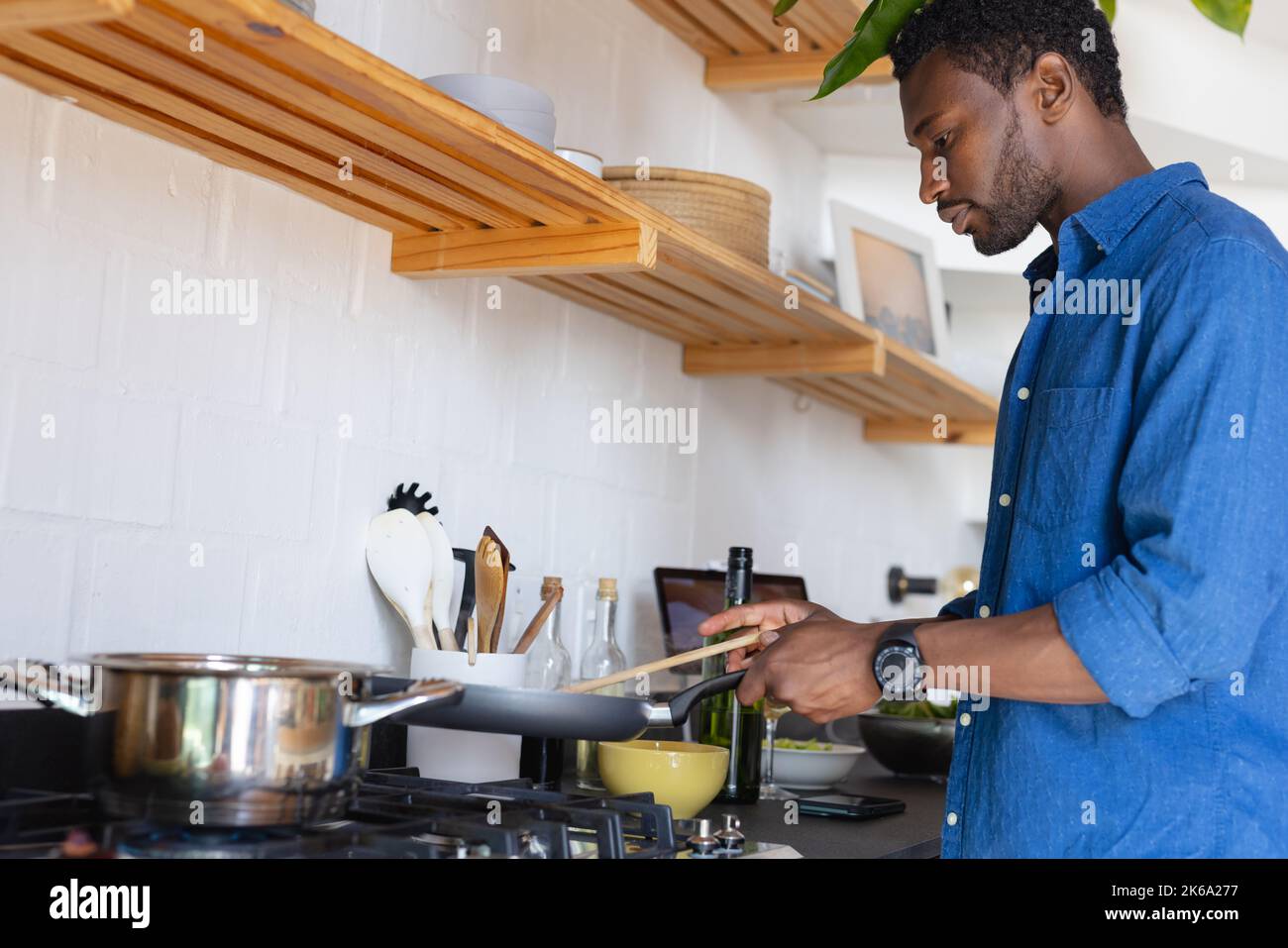 Happy african american man standing in kitchen and cooking dinner Stock ...