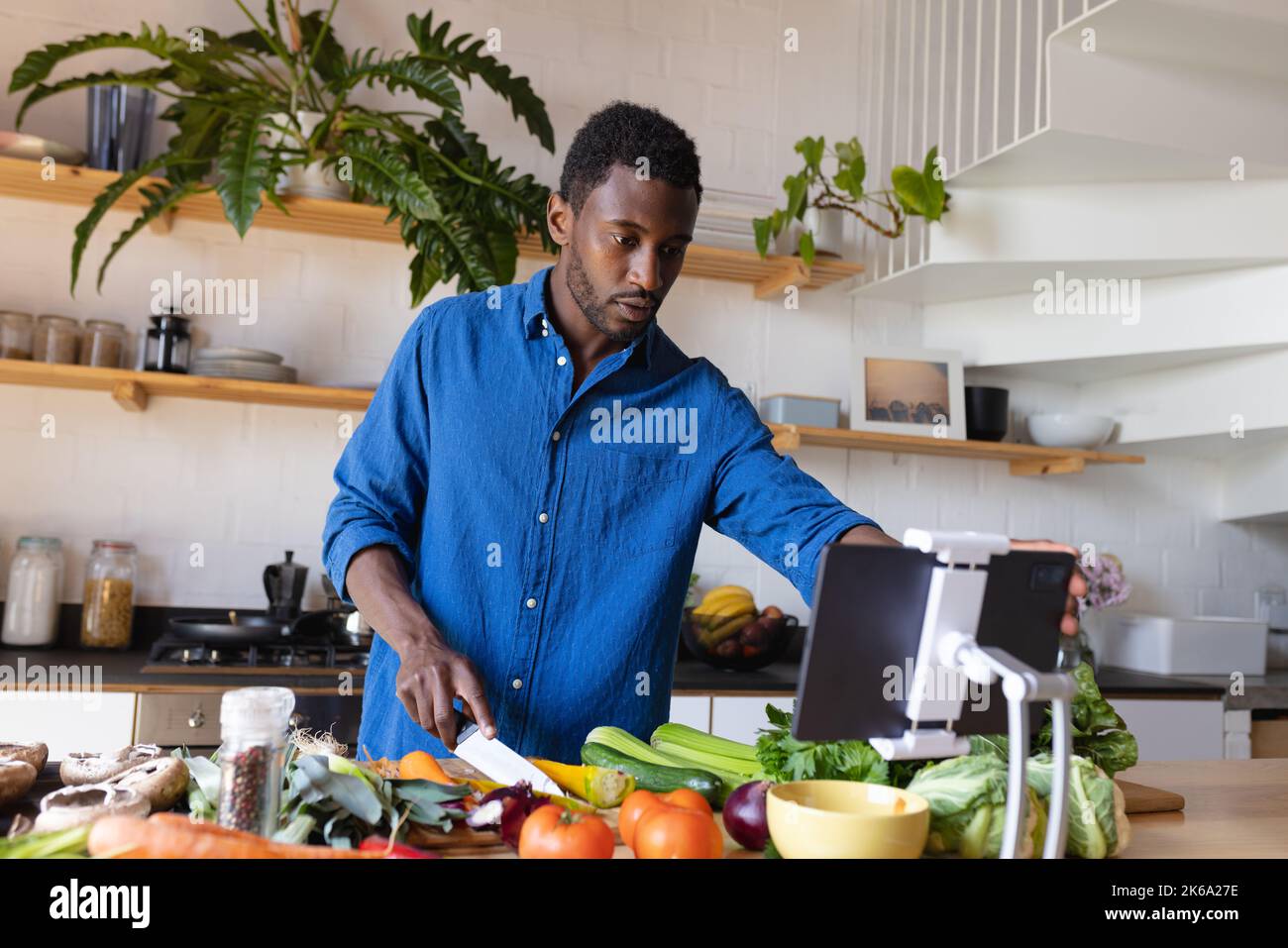 Happy african american man cooking dinner in kitchen, using tablet ...