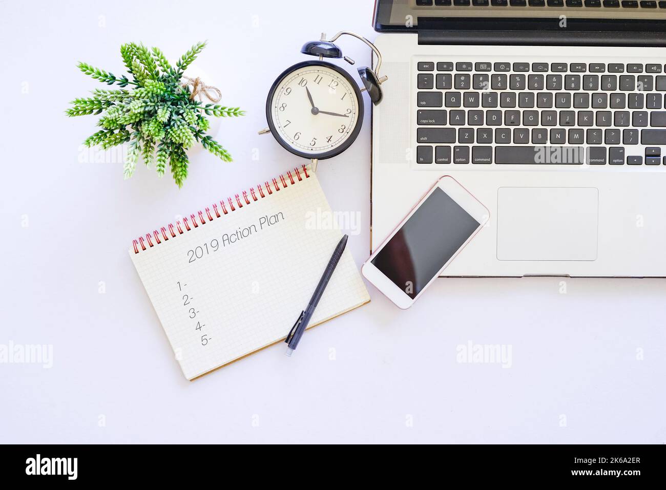 Top view of office table with black alarm clock, laptop and notepad ...