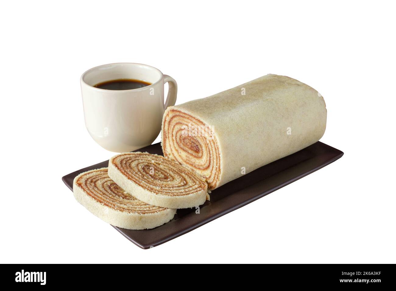 Sliced bolo de rolo on a brown plate next to a cup of coffee (white ...