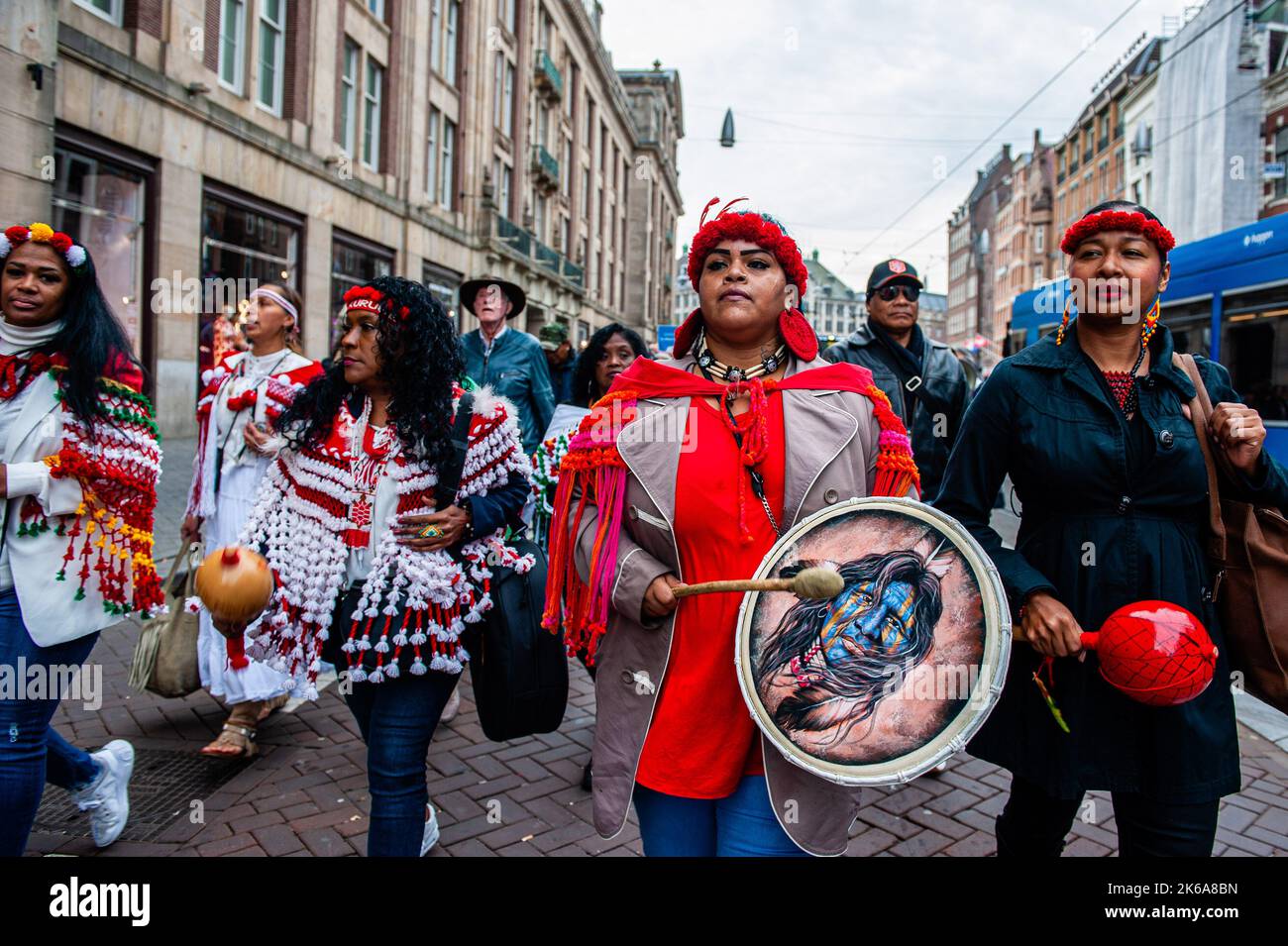 An Indigenous woman is seen walking while playing a traditional drum ...