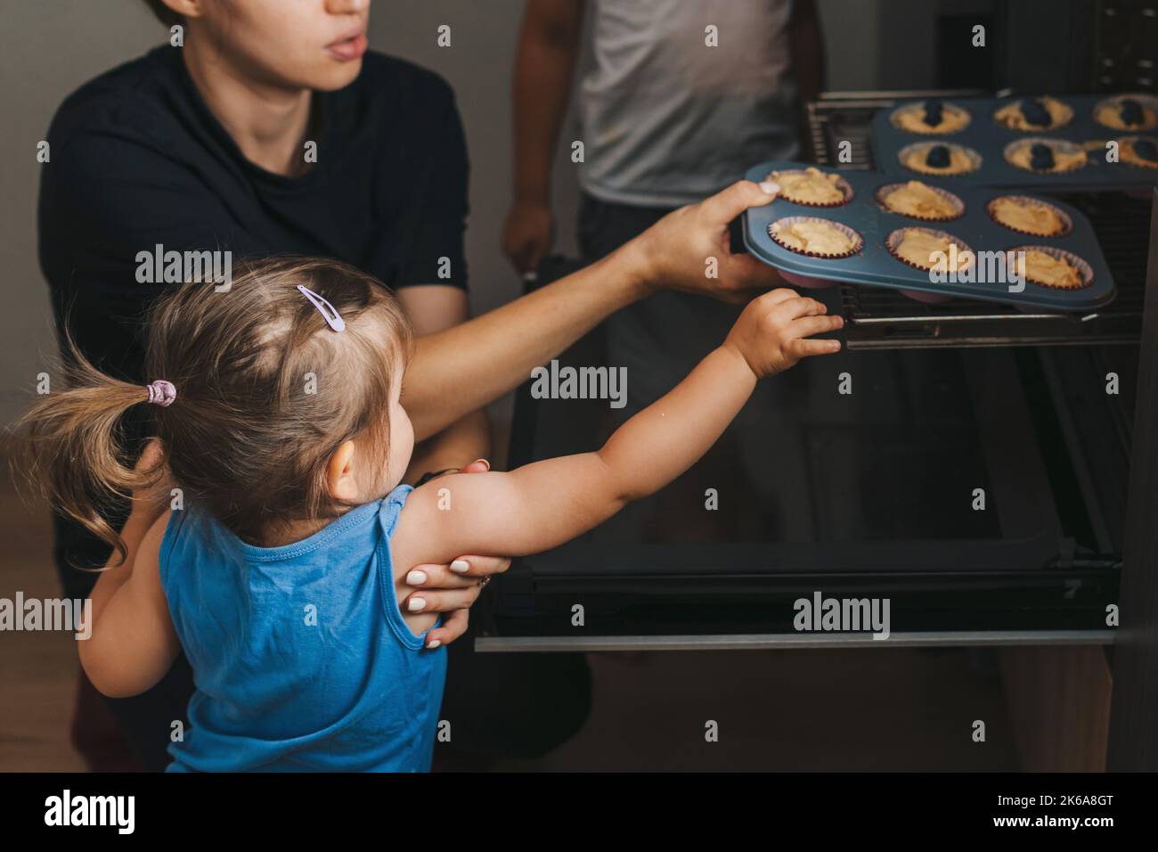 Woman with a little daughter with taking out a baking sheet with baked ...