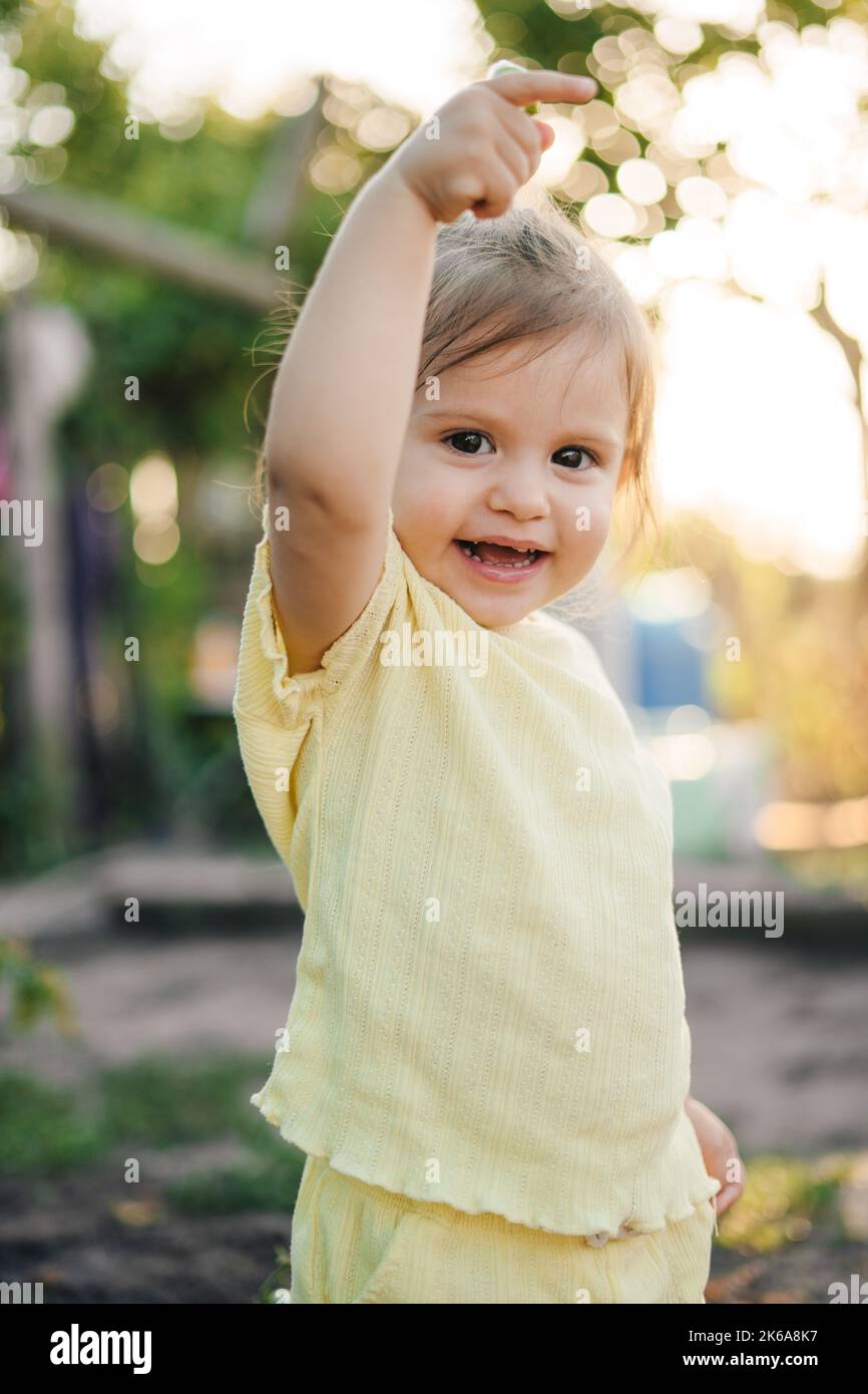 Portrait of baby girl, happily pointing her finger of the right hand ...