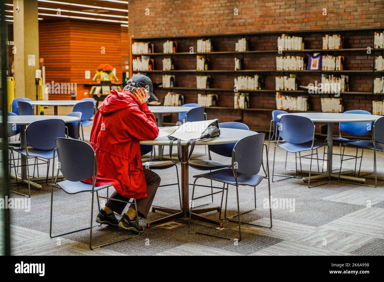 Old senior female reading newspaper inside a library Stock Photo - Alamy