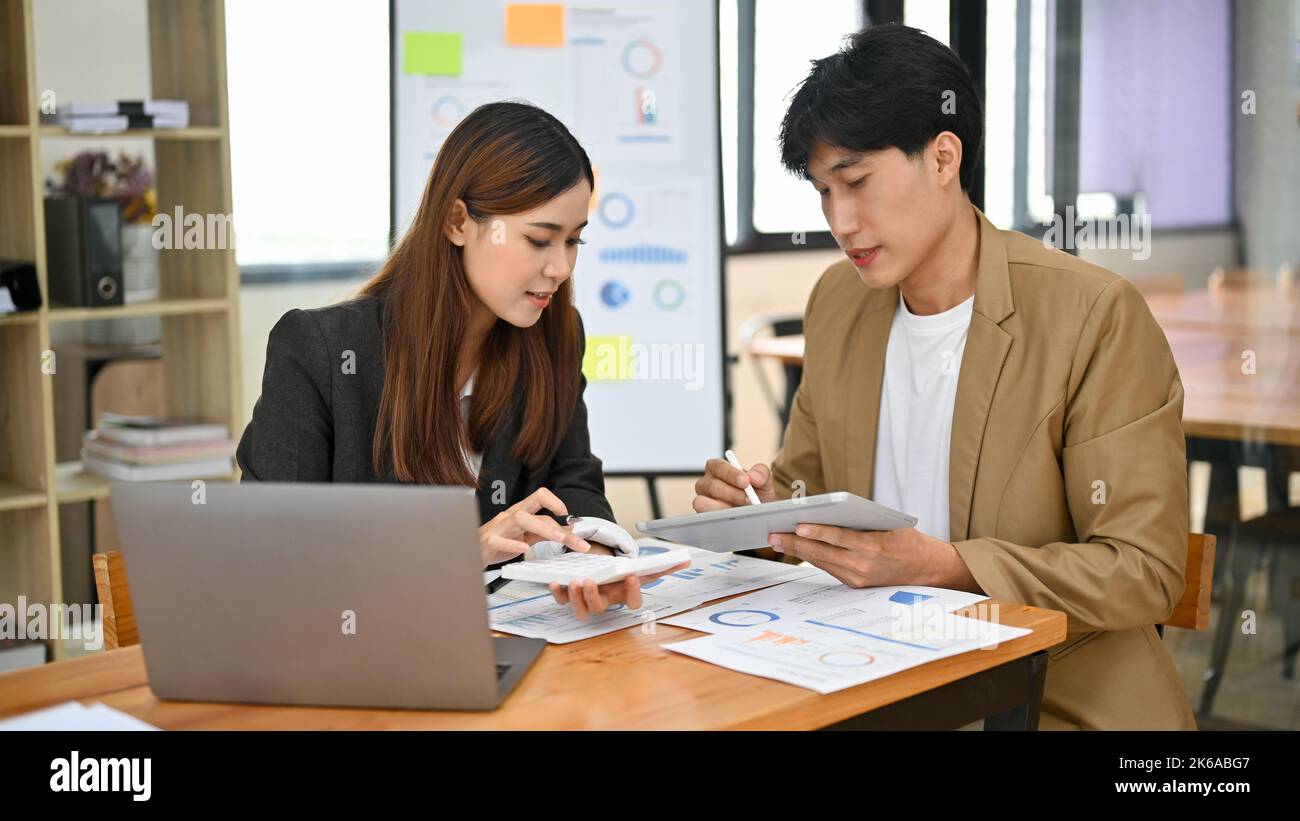 Two young Asian female and male accountants working together ...