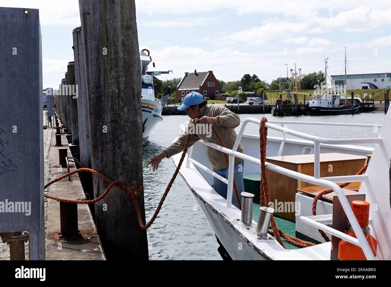 Sailor throwing rope over a bollard while making fast his ship, Amrum ...