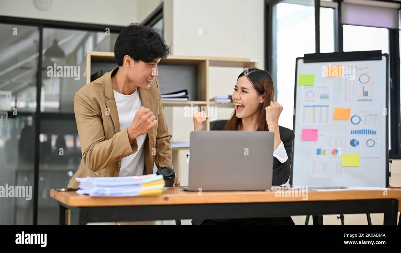Excited and overjoyed young Asian male and female colleagues hands up ...