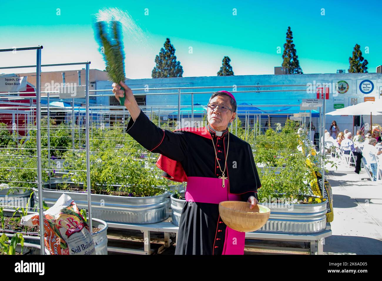 An Asian American Catholic bishop sprinkles holy water while blessing a ...
