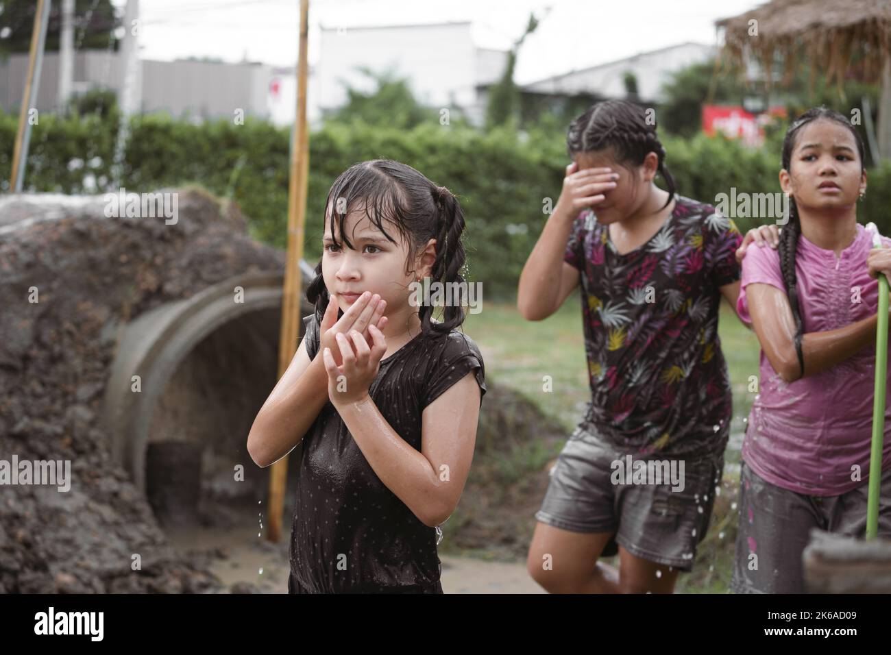 Group of happy children girl playing in wet mud puddle during raining ...