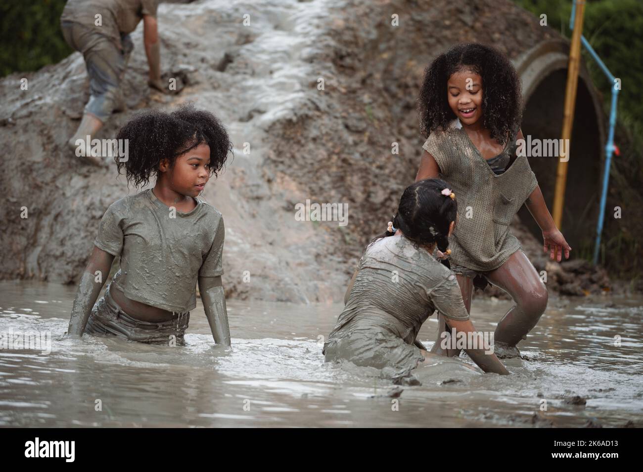 Group of happy children girl playing in wet mud puddle during raining ...