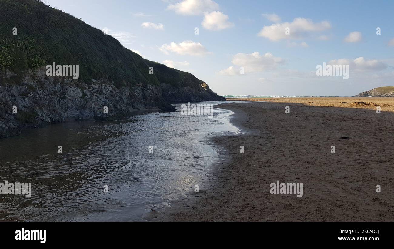 A shore with a huge sea stack and a cloudy blue sky in the background ...