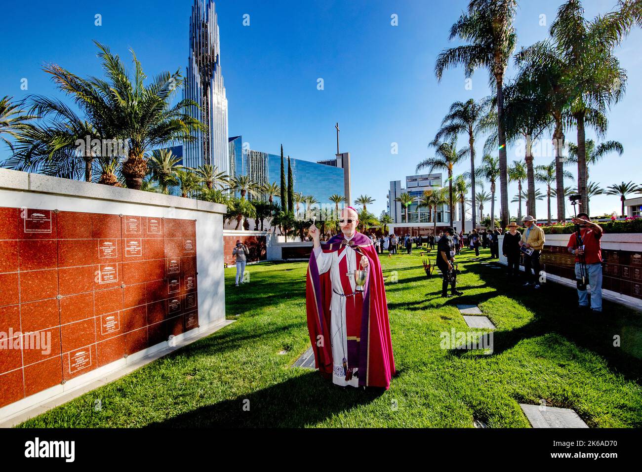 Sprinkling holy water with an aspergillum, a bishop conducts a ...