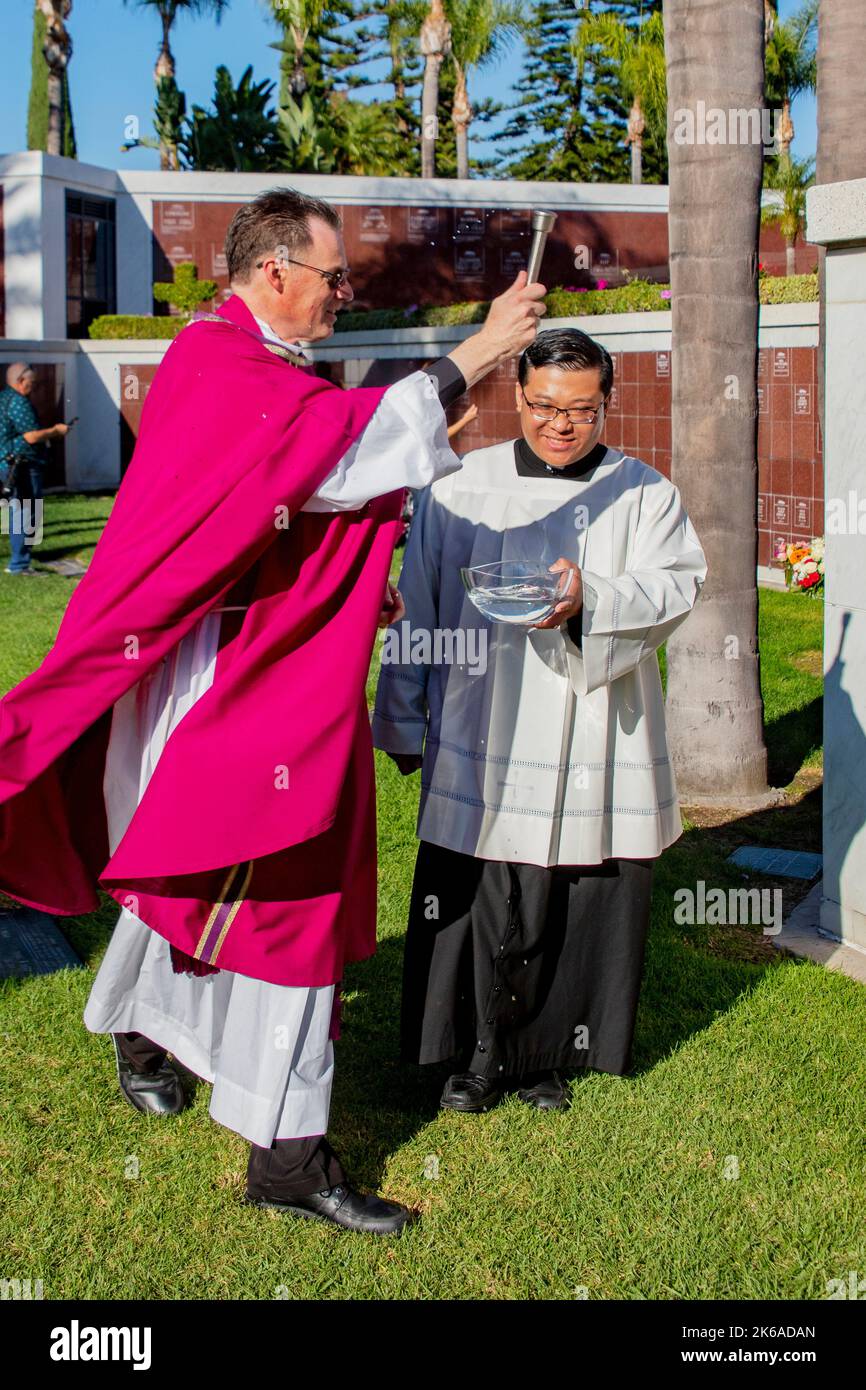 Using an aspergillium, a priest prepares to sprinkle holy water in the ...