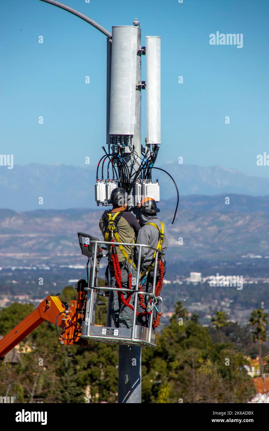 Using a portable cherry picker crane, maintenance workers repair a ...