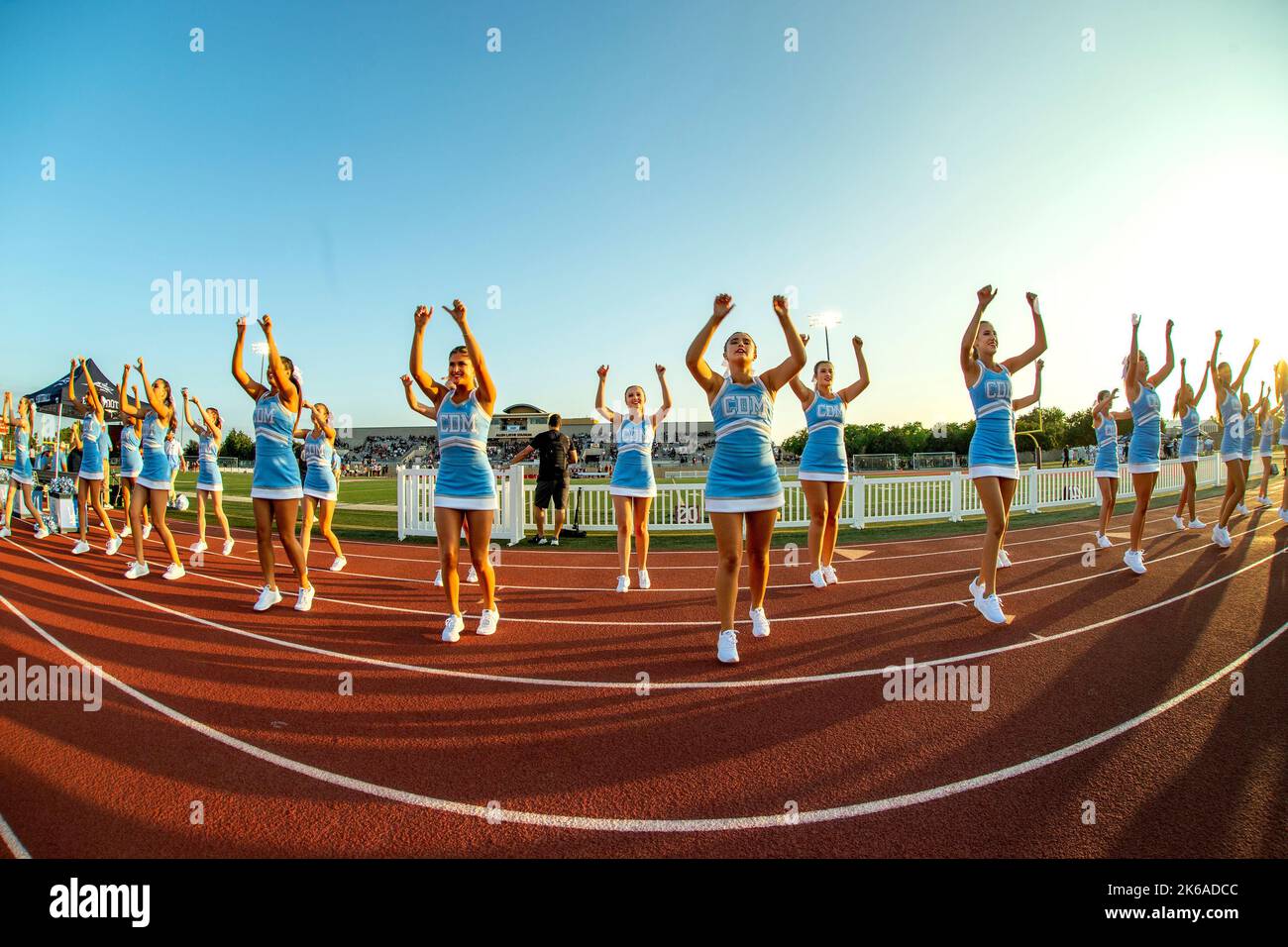 Blue-uniformed multiracial high school cheerleaders exercise to limber ...