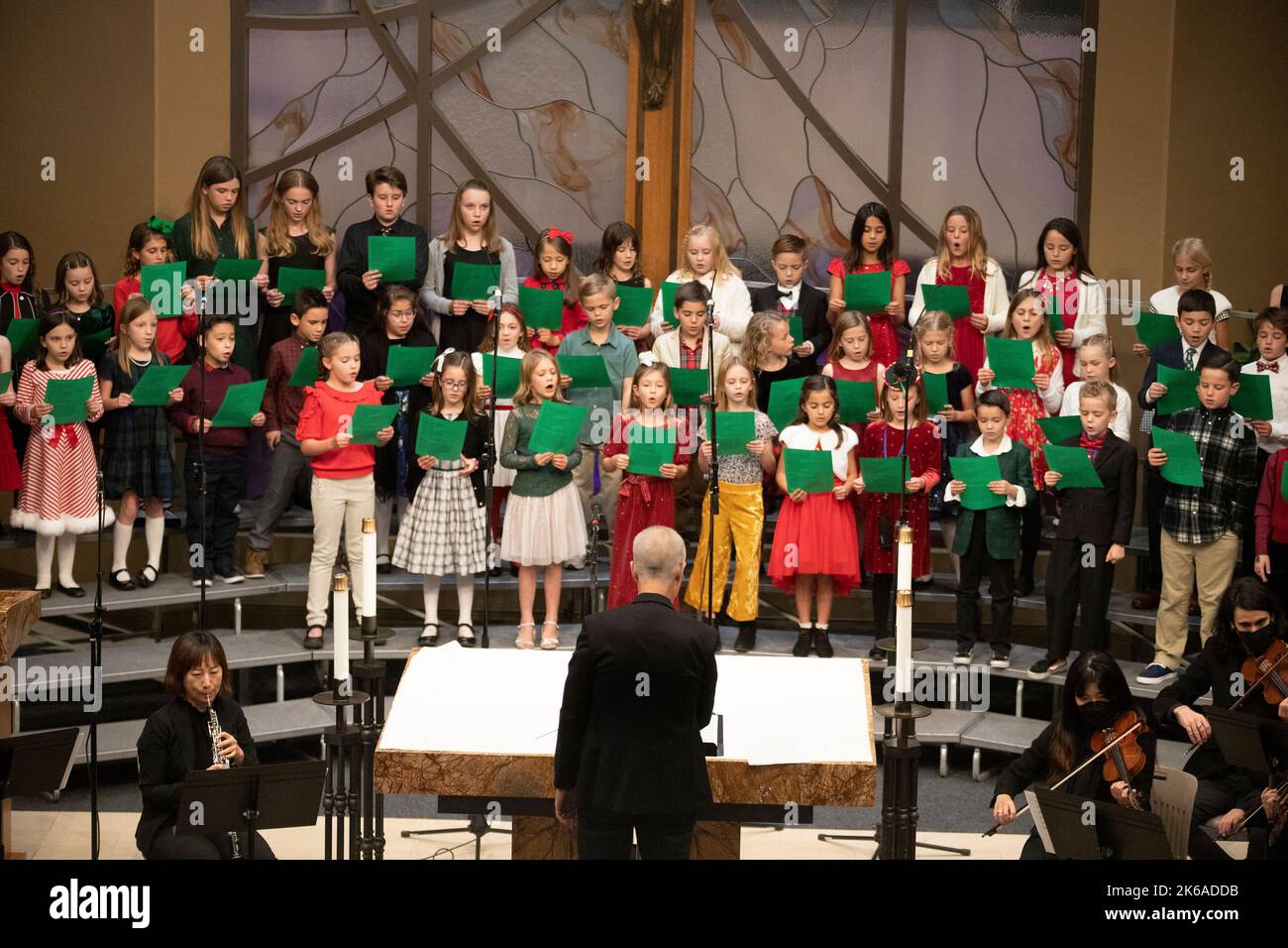 Holding lyric sheets, boys and girls sing in a Christmas choir at a ...