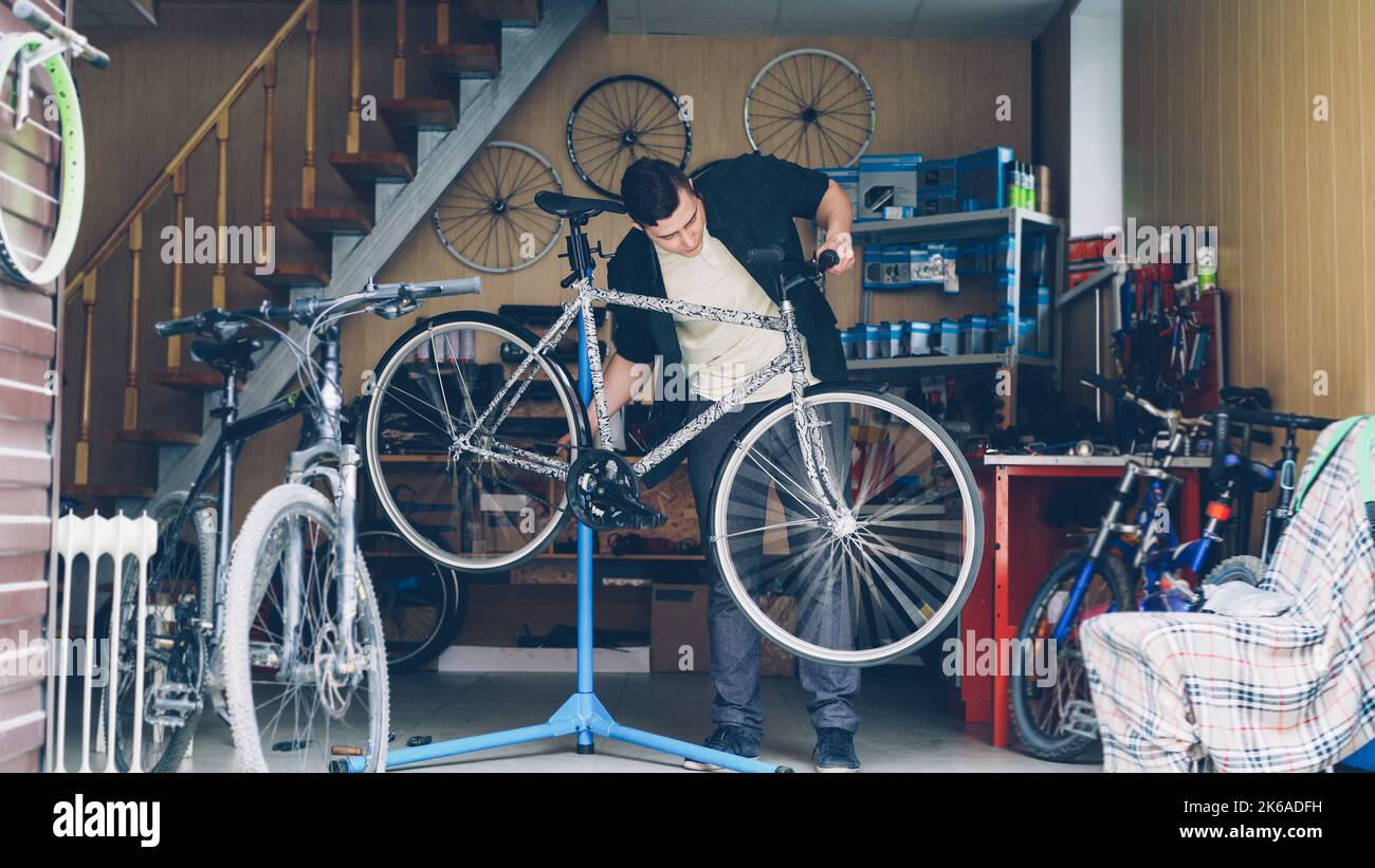 Skilled male mechanic is fixing broken bicycle wheel with wrench then ...