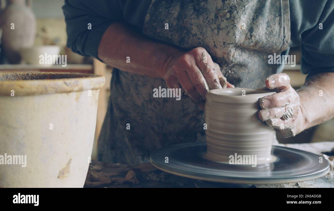 Close-up shot of half-finished ceramic vase spinning on potters's wheel ...