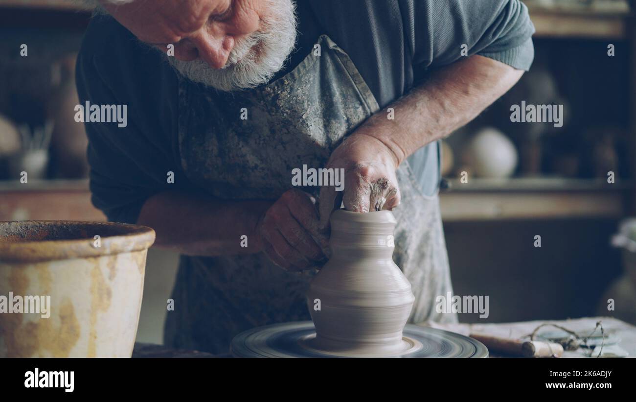 professional male potter creating jar from brown clay in workplace ...