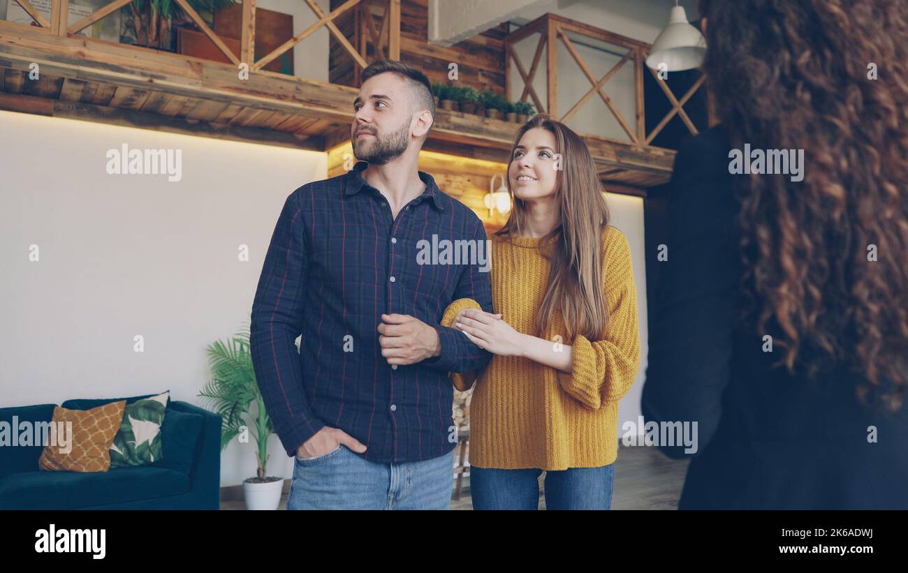 Confident housing agent is showing spacious modern house with beautiful ...