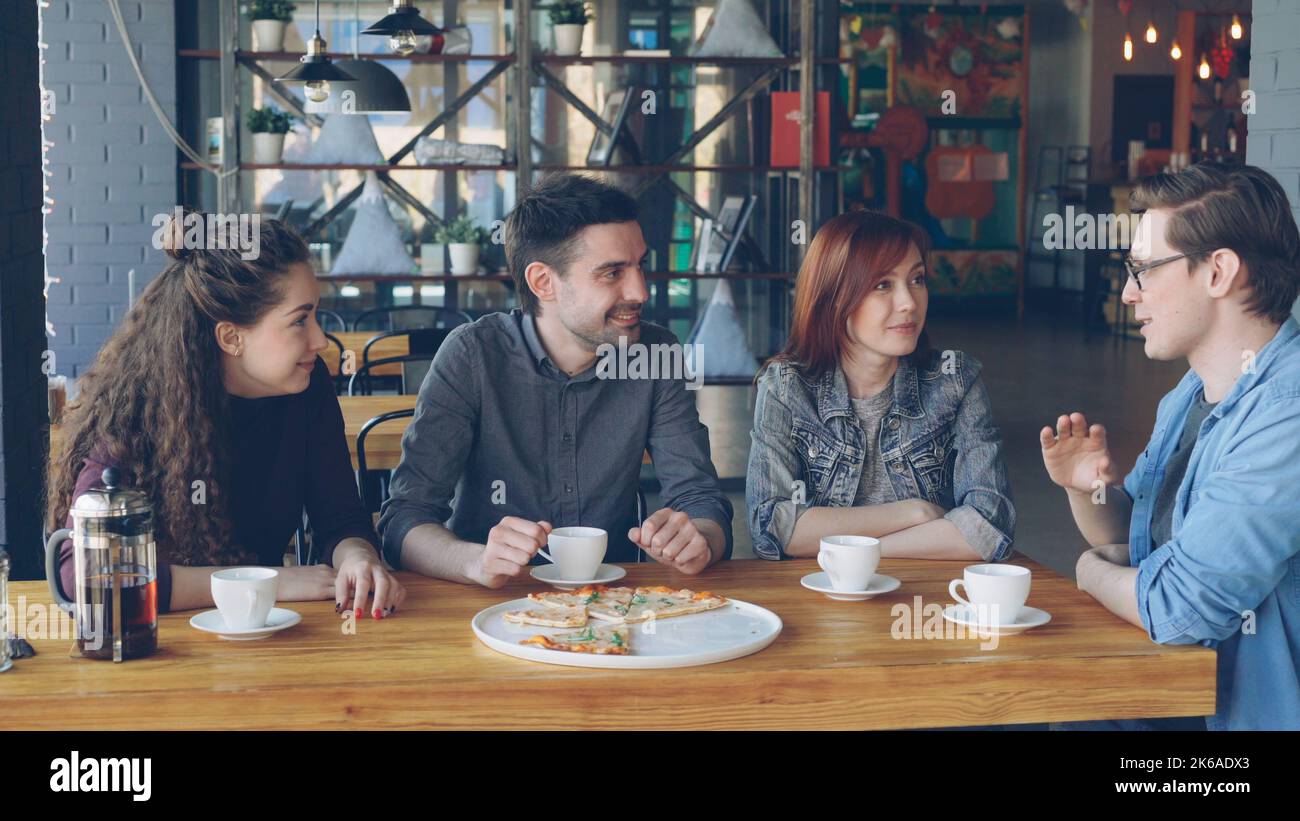 Happy handsome guy is telling funny story to his friends while dining ...