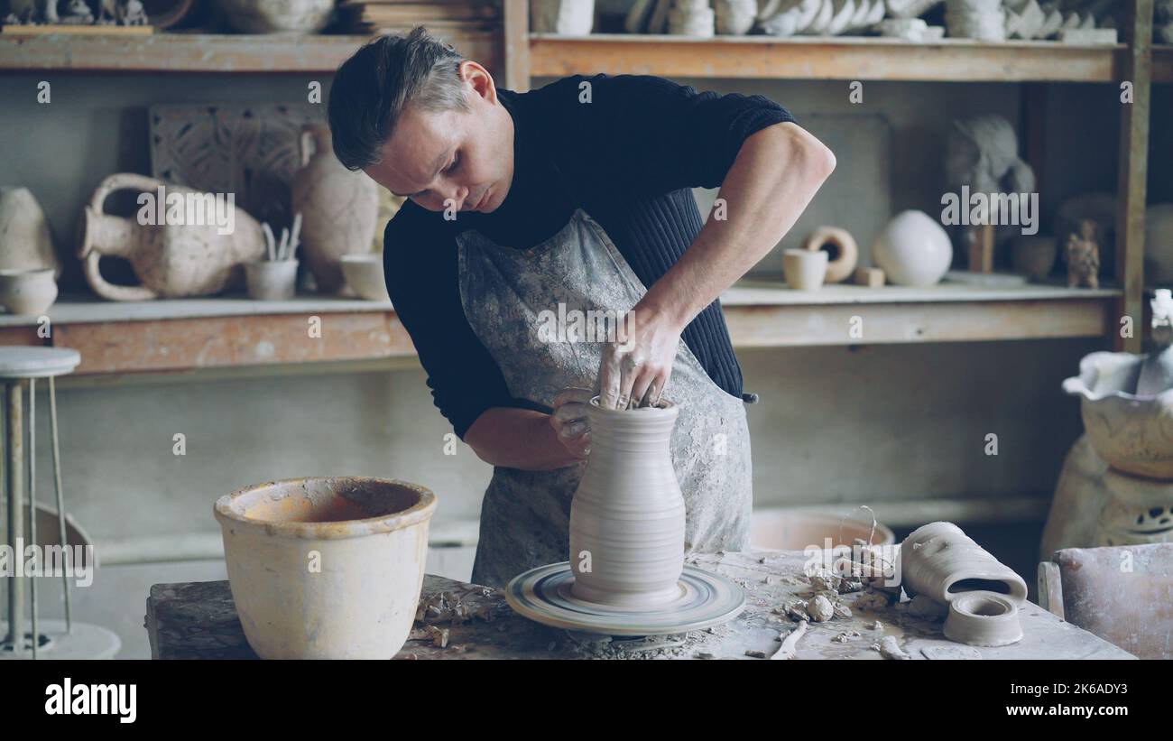 Skillful young potter is molding beautiful ceramic vase from clay on ...