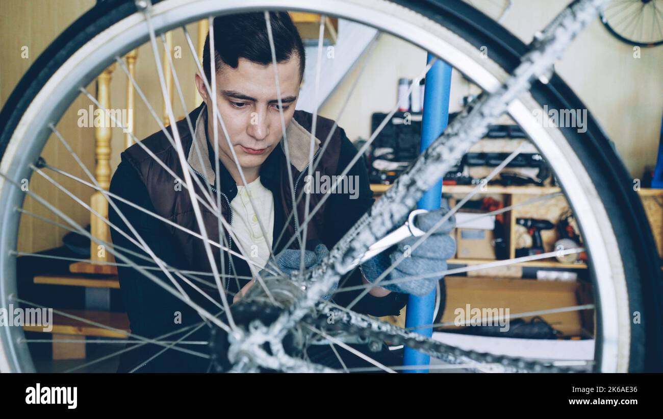 Concentrated handsome guy skilled mechanic is repairing bicycle wheel ...