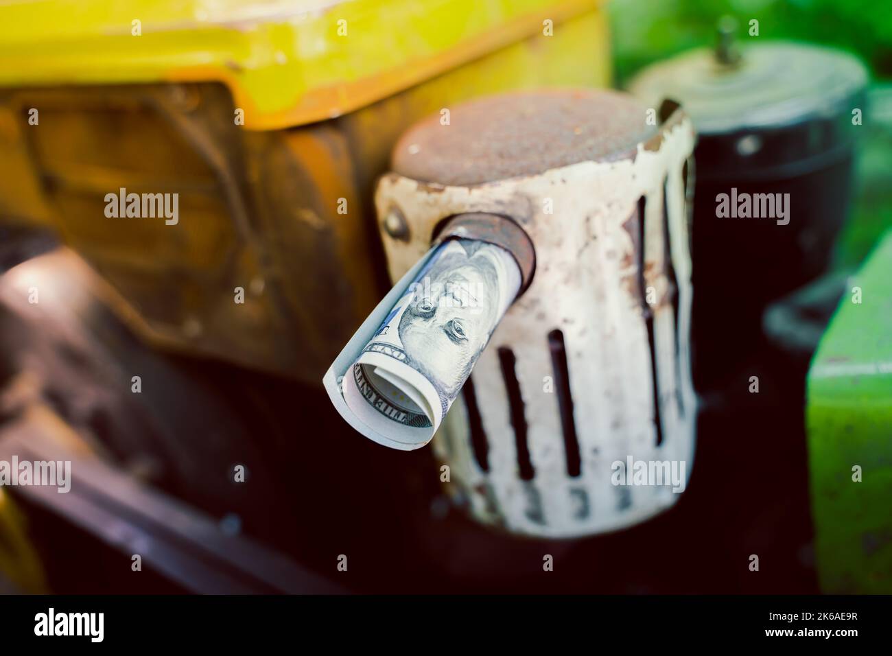 A hundred dollar bill rolled into a tube sticks out of the exhaust pipe ...