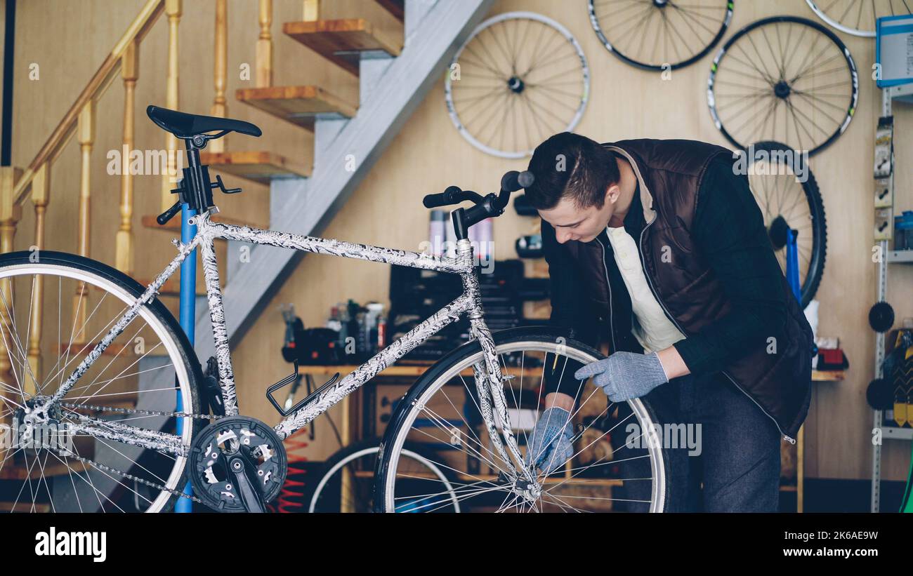 Handsome male mechanic is repairing broken wheel of bicycle with ...