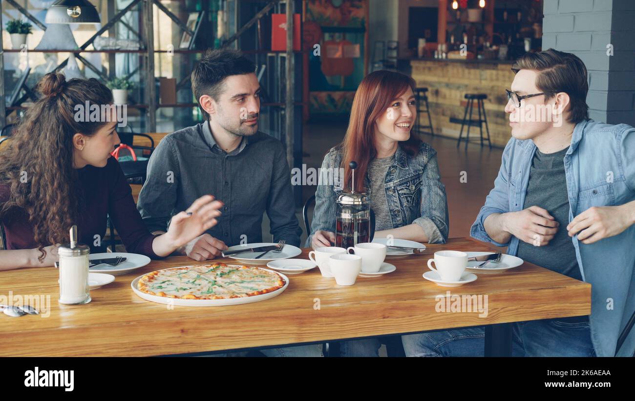 Cheerful young friends are talking and gesturing sharing news while ...