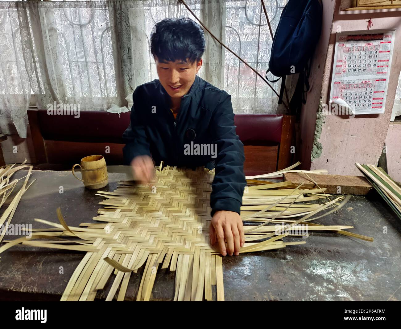 Sikkim, India - June 17 2022, An Indian craftsman weaves a cane Sitting ...